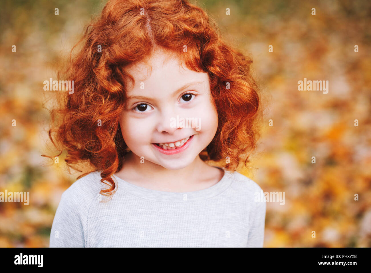 Closeup portrait of cute adorable smiling little red-haired Caucasian ...