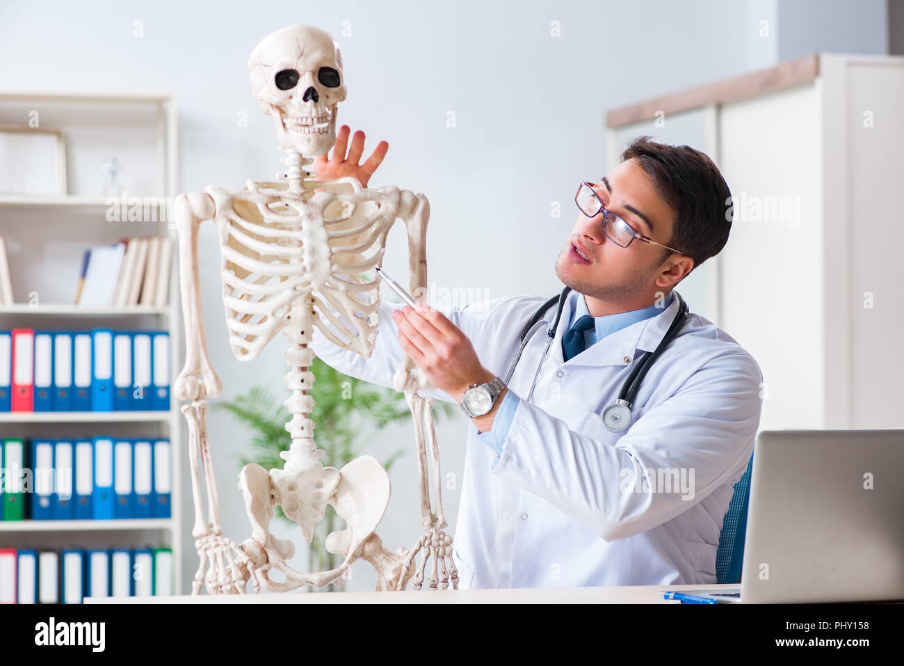 Yong male doctor with skeleton isolated on white Stock Photo - Alamy