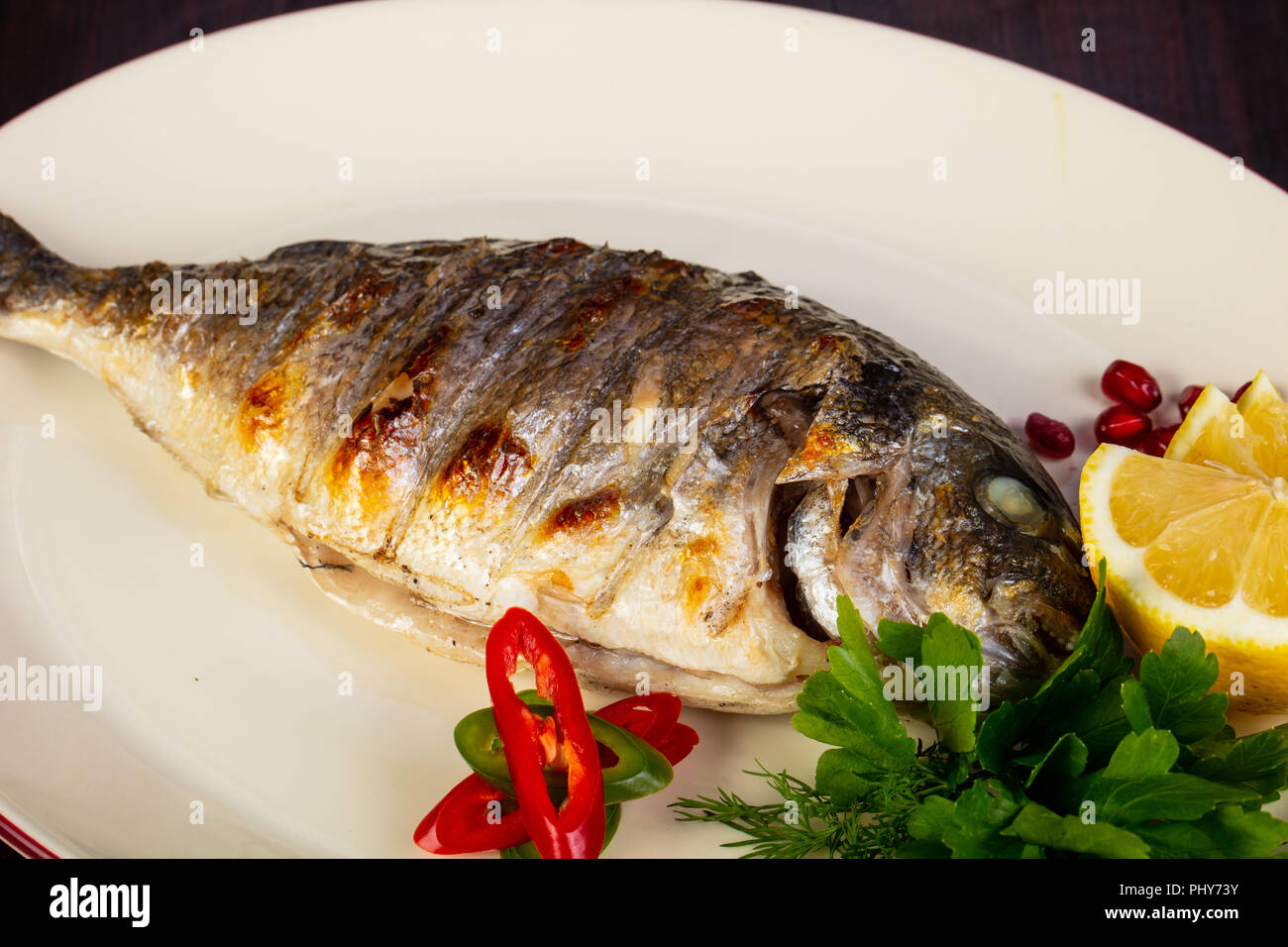 Grilled dorada served lemon and herbs Stock Photo - Alamy