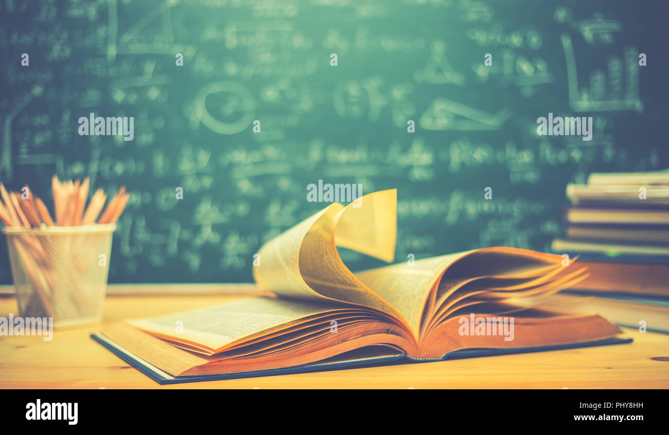 School books on desk formulas and Physics inscription on the blackboard ...