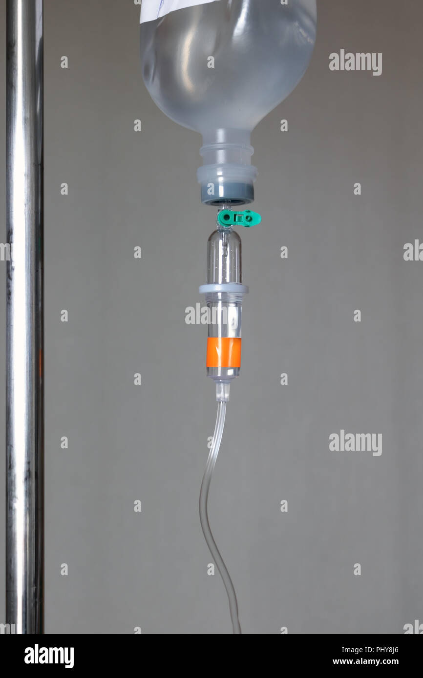 A stand with drip bag against wall. Close up saline solution drip for ...