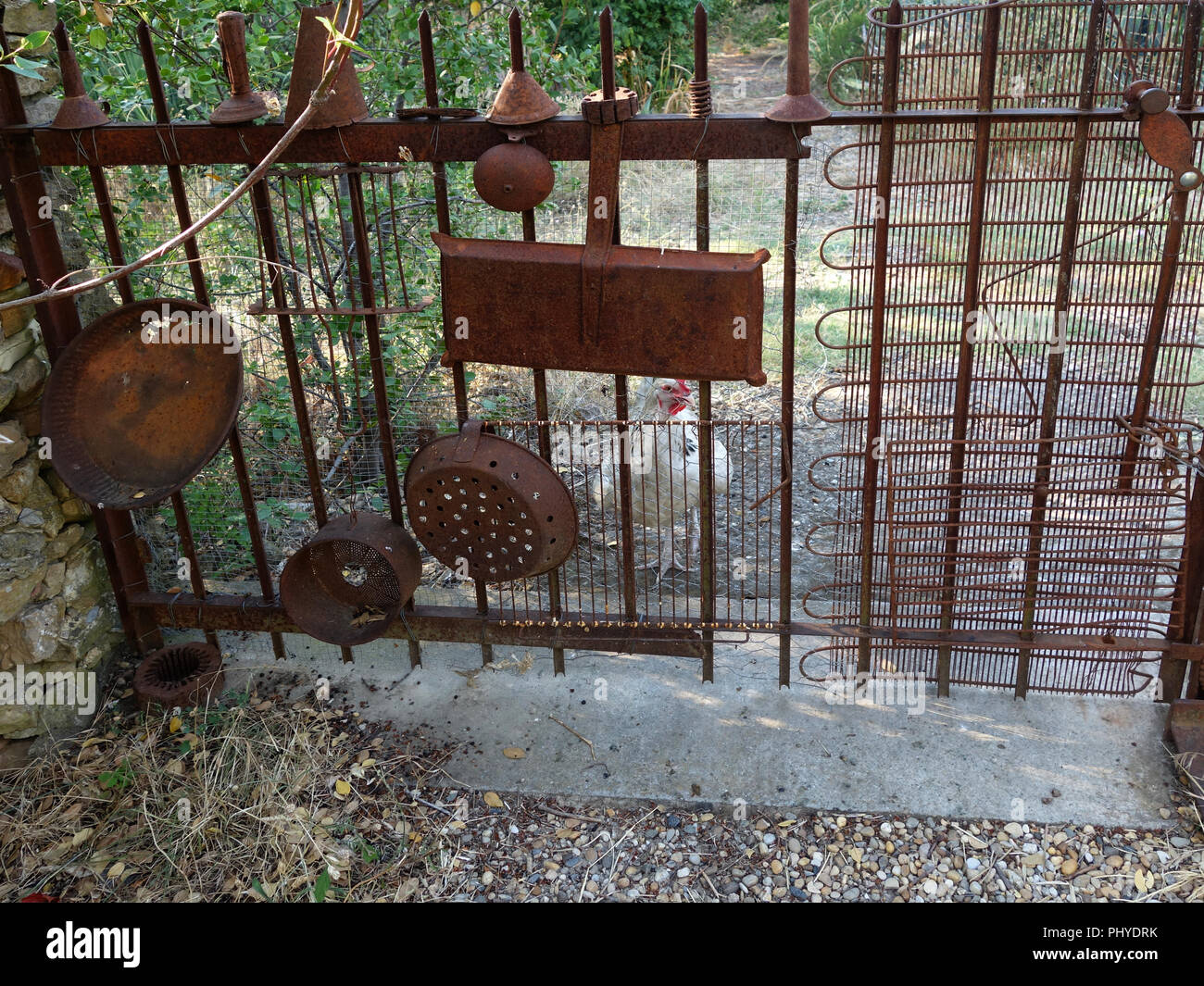 Quirky hand made gate made from old recycled metal items on land at a ...
