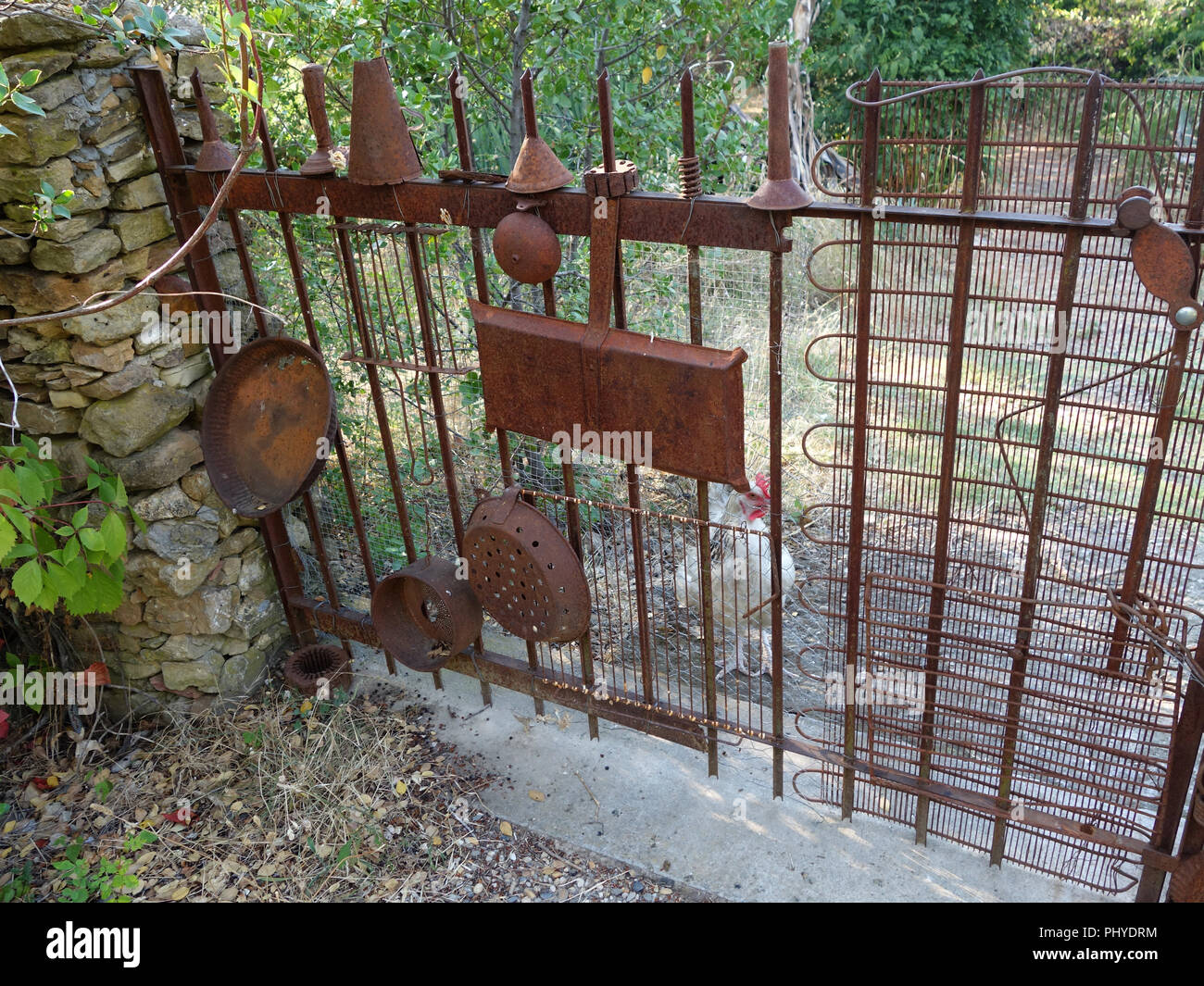 Quirky hand made gate made from old recycled metal items on land at a ...