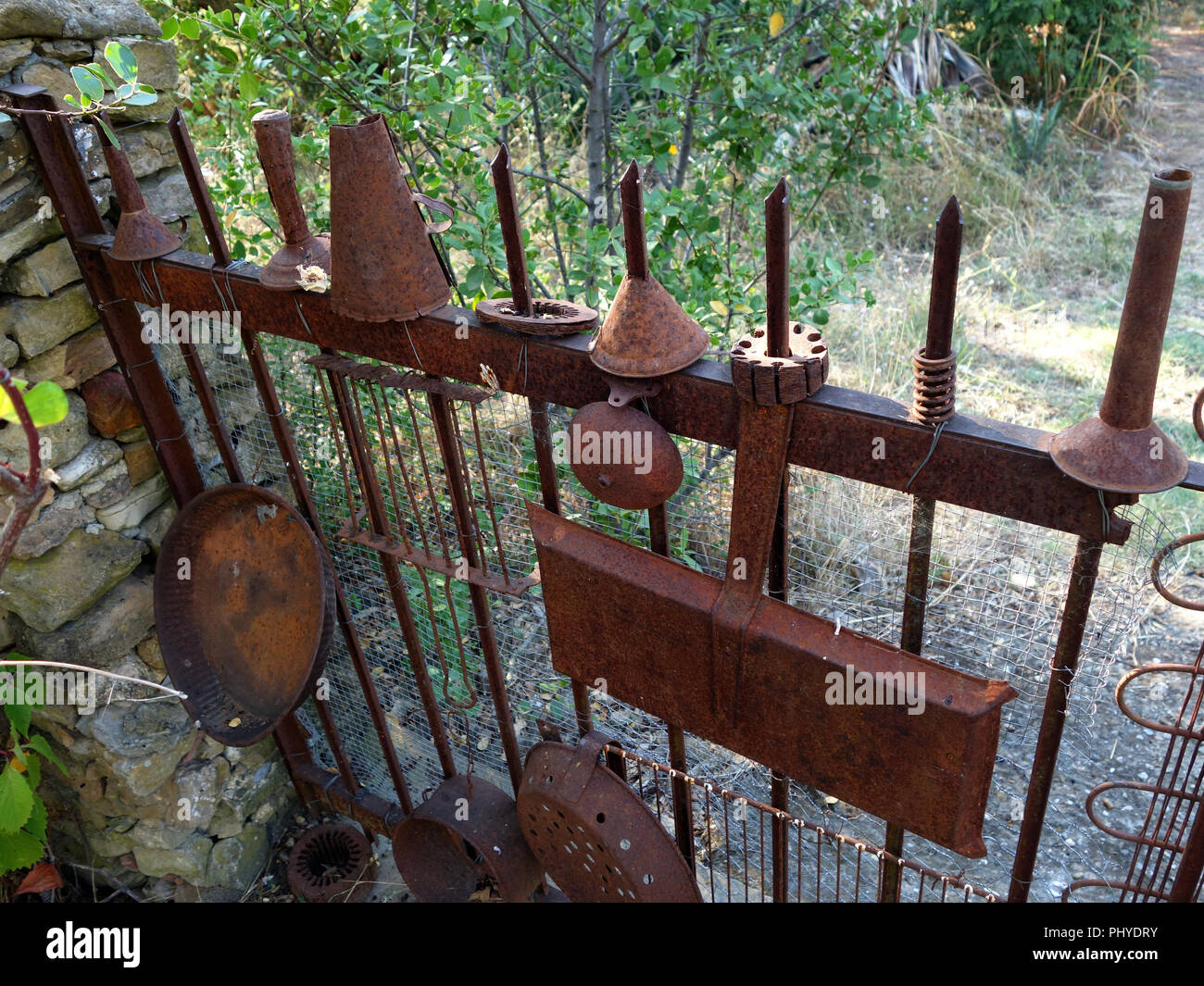 Quirky hand made gate made from old recycled metal items on land at a ...