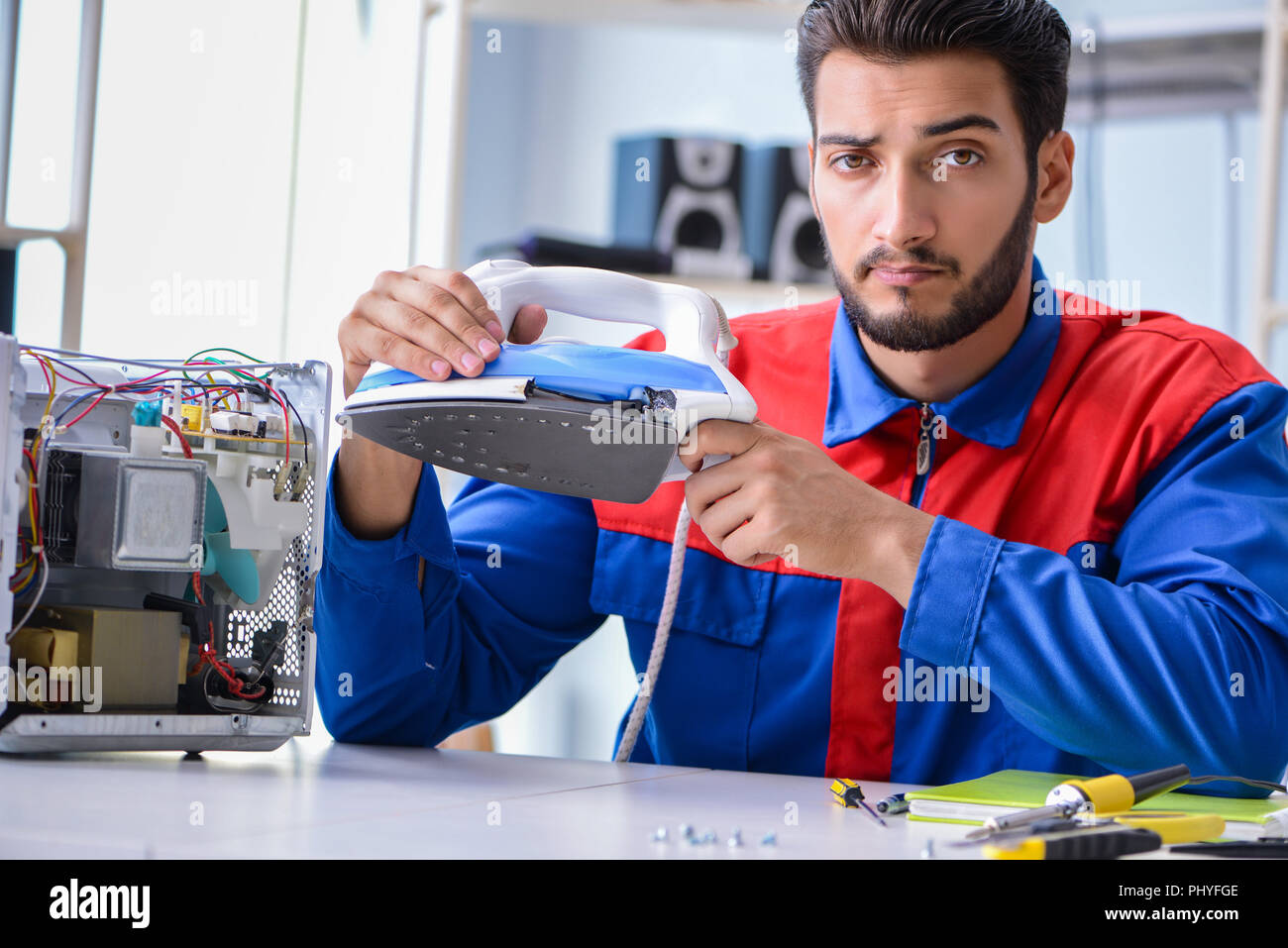 Man repairman repairing iron at service center Stock Photo - Alamy