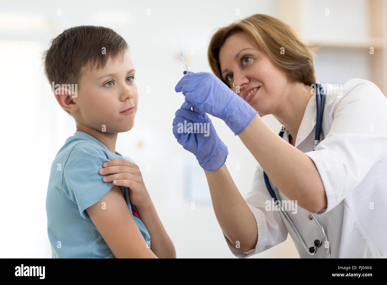Doctor holds syringe and teenager patient. Little brave boy before ...
