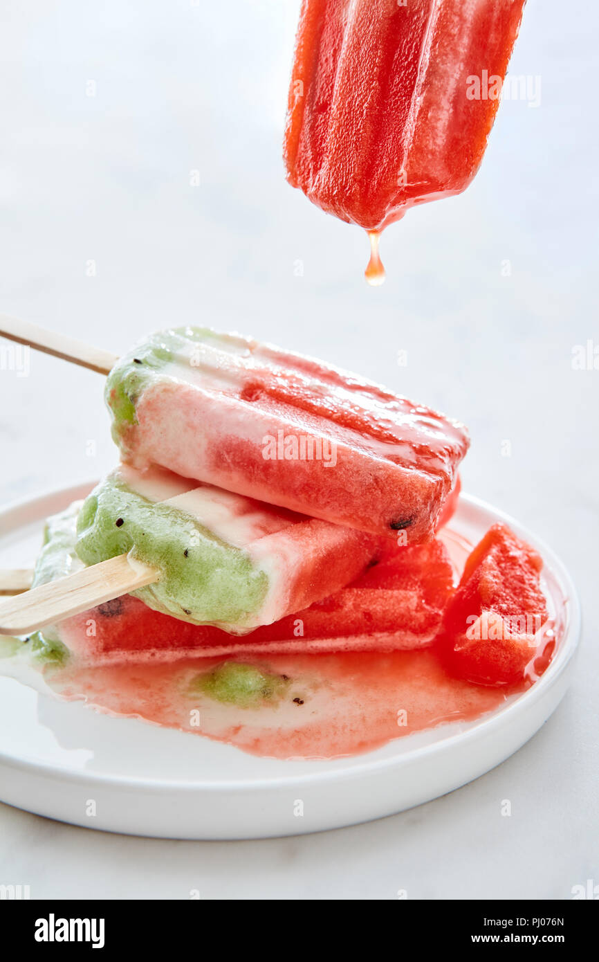 Fruit melting ice cream, drops dripping into a plate with a stack of ...