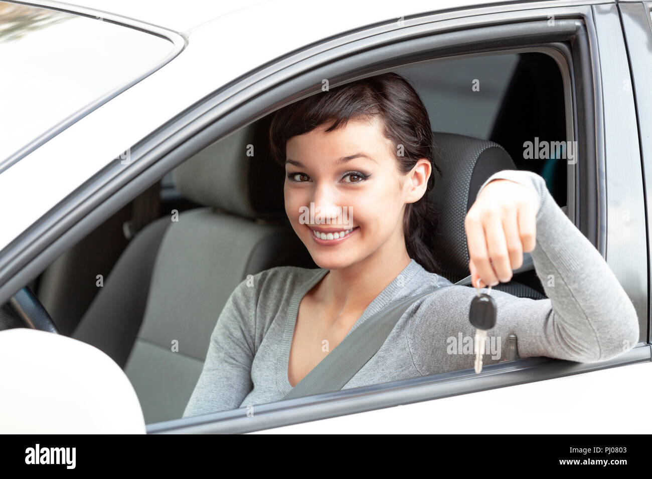 Happy owner of a new car is showing the car key. Pretty girl driver ...