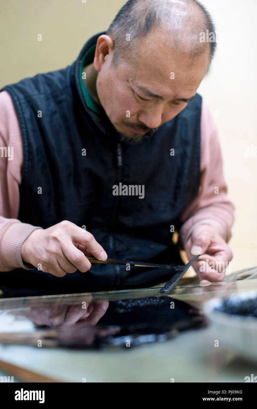 Tetsuyohi Kon decorates a fan handle with lacquer using an implement ...
