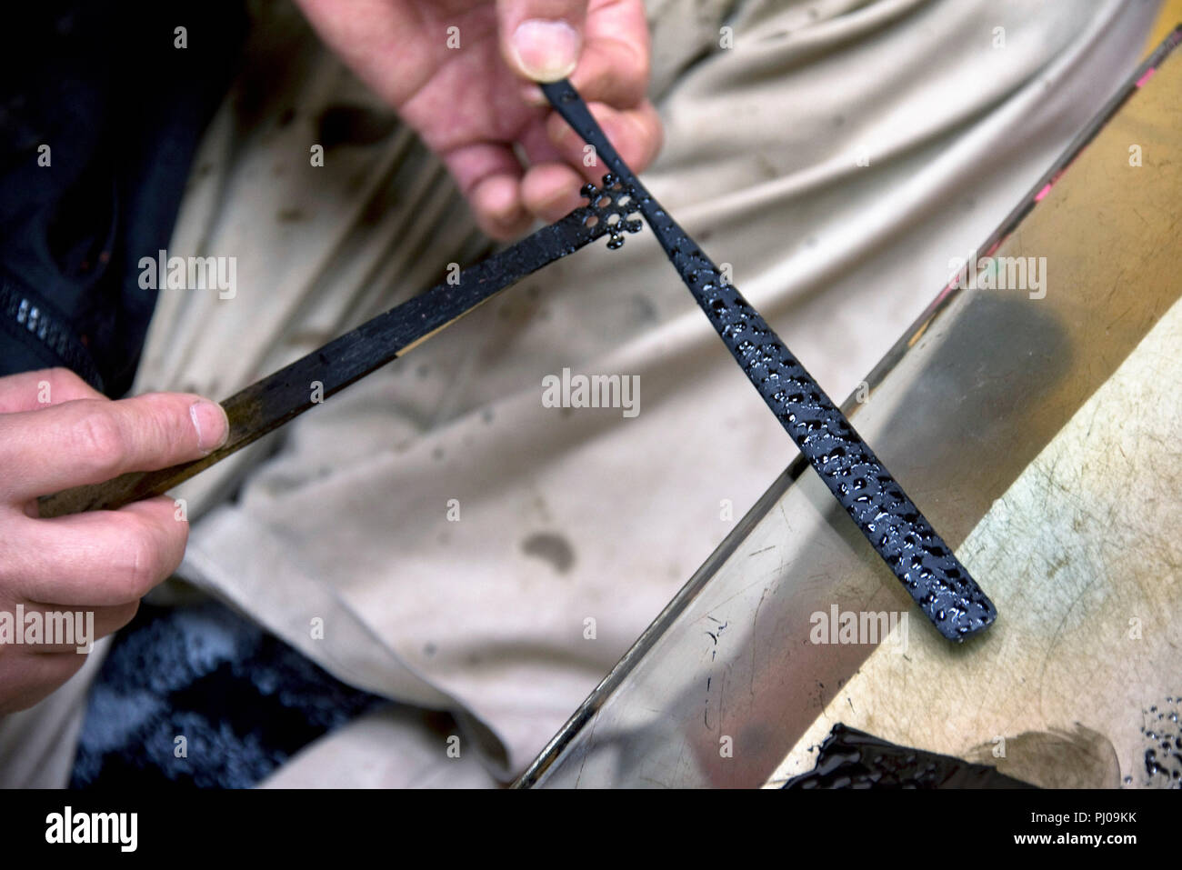 Tetsuyohi Kon decorates a fan handle with lacquer using an implement ...