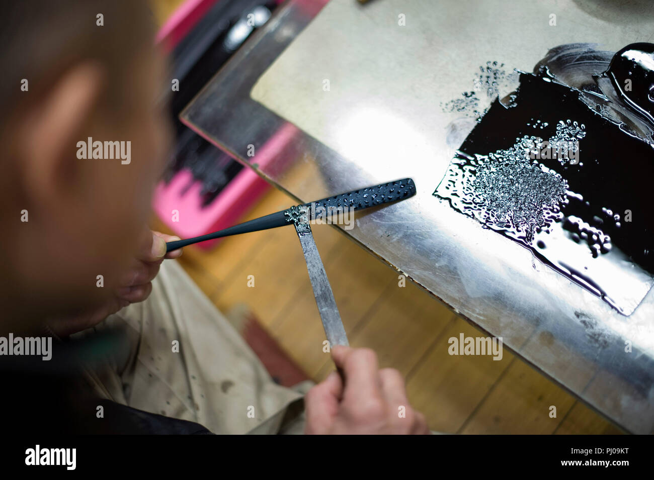 Tetsuyohi Kon decorates a fan handle with lacquer using an implement ...
