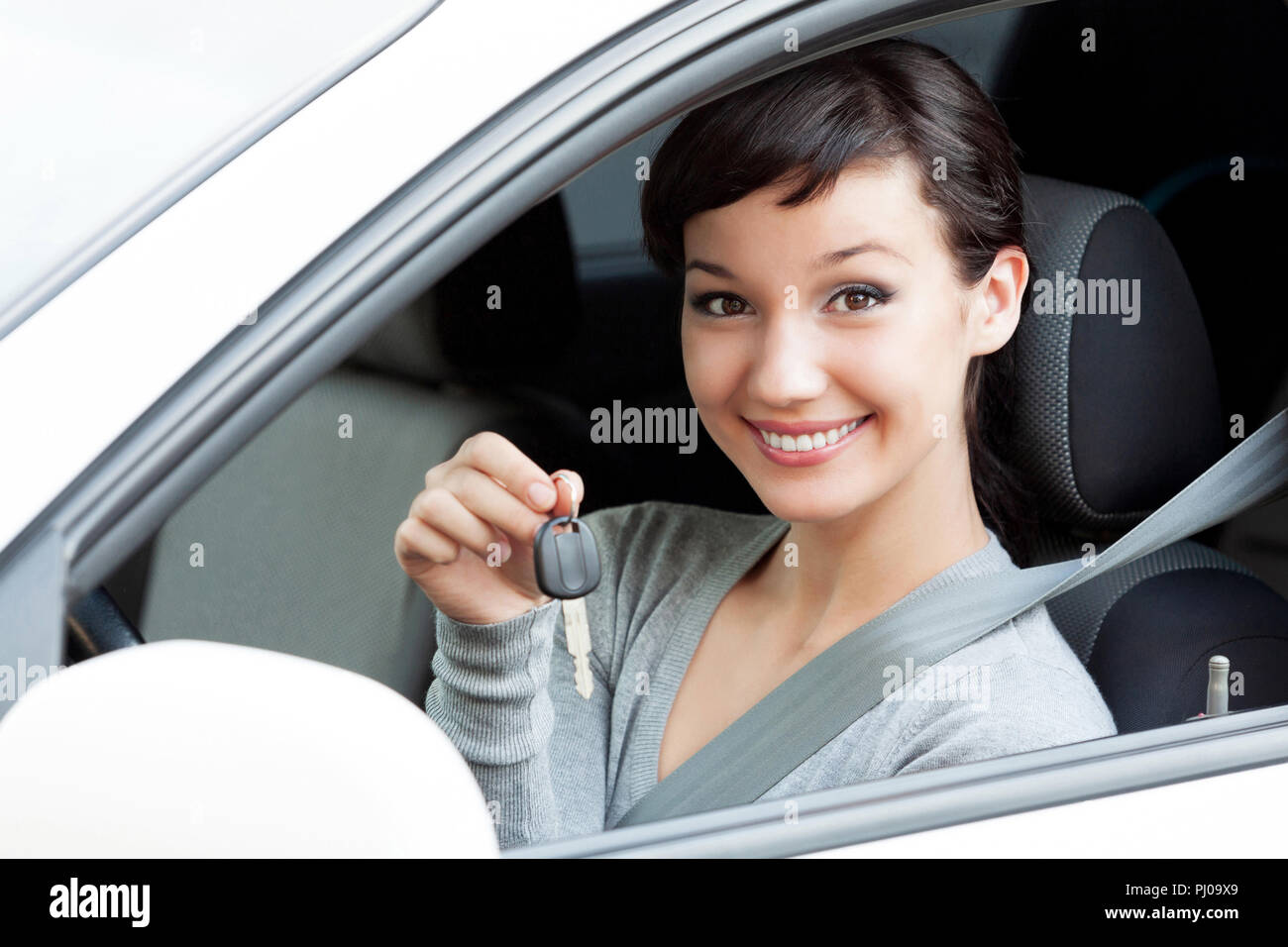 Happy owner of a new car is showing the car key. Pretty girl driver ...