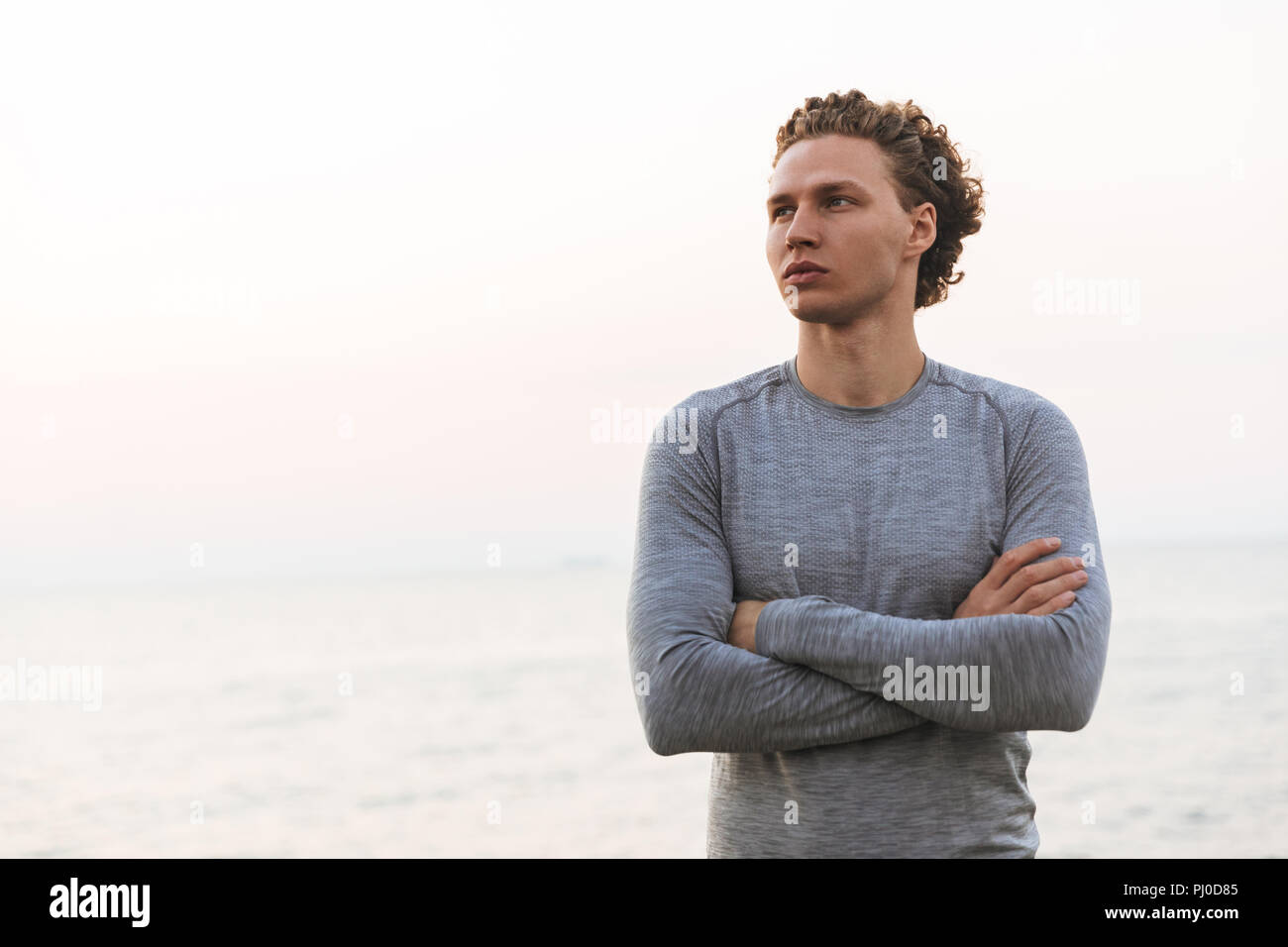 Photo of handsome strong young sportsman standing outdoors at the beach ...