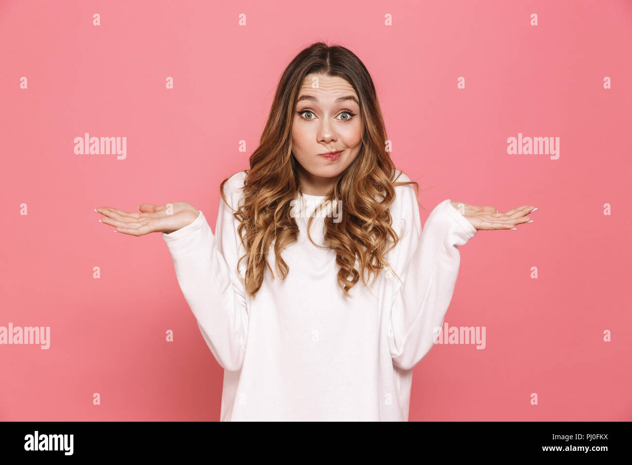 Portrait of a confused young casual girl shrugging shoulders isolated ...