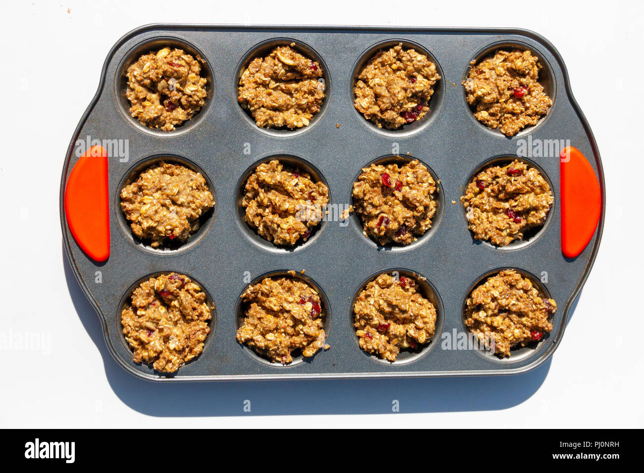 A top view of a muffin pan with uncooked bran muffin mixture waiting to ...