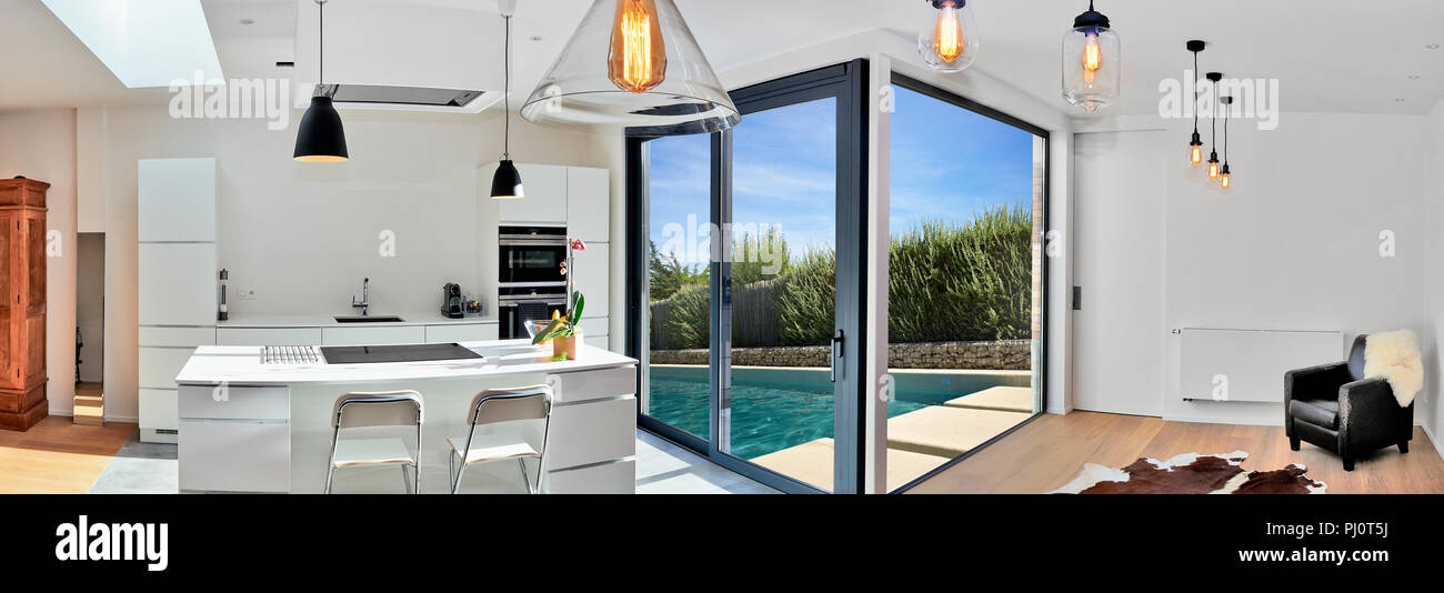 Open modern kitchen from loft with view on a lush garden and swimming ...