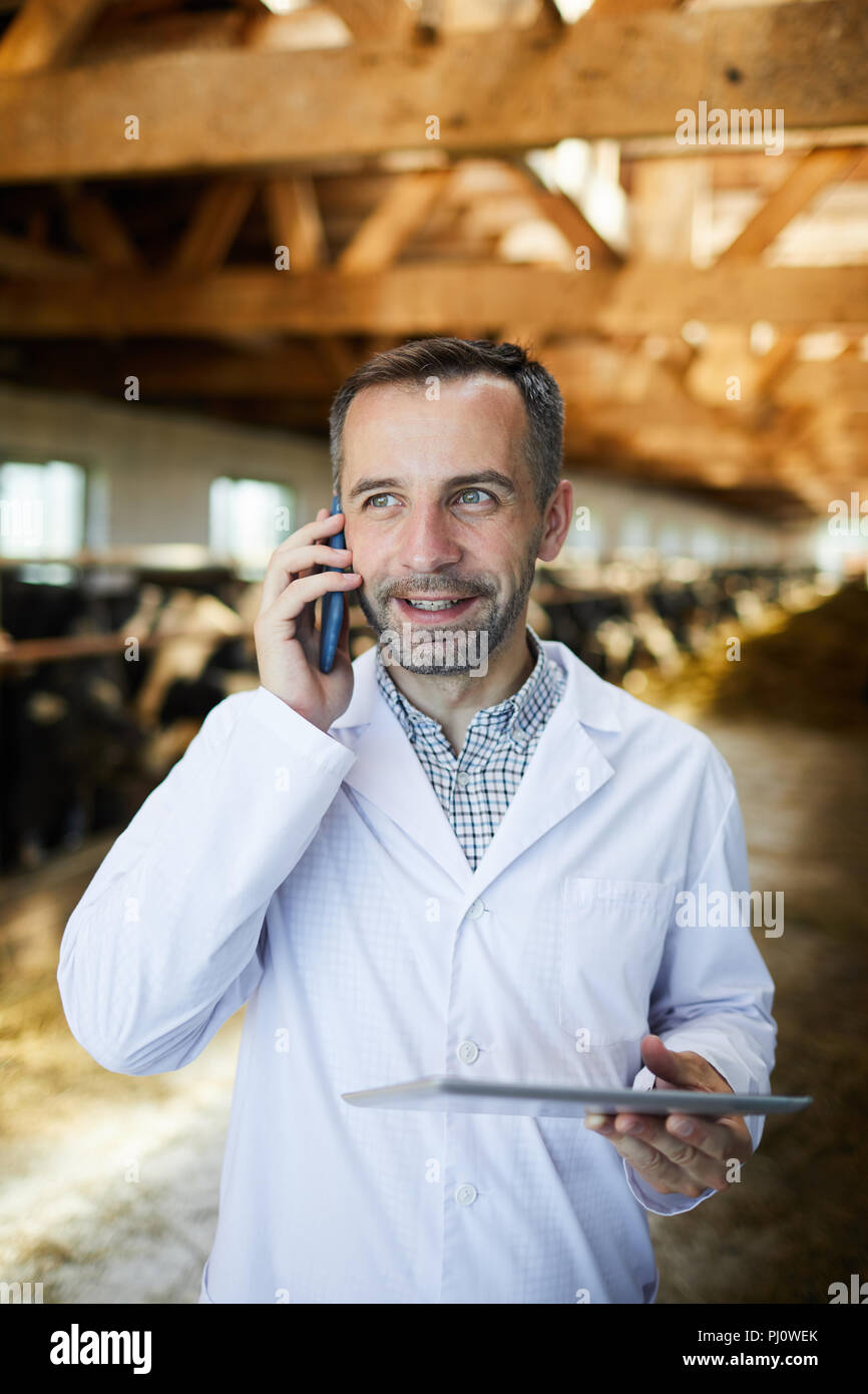 Mature Farm Vet Speaking by Phone Stock Photo - Alamy
