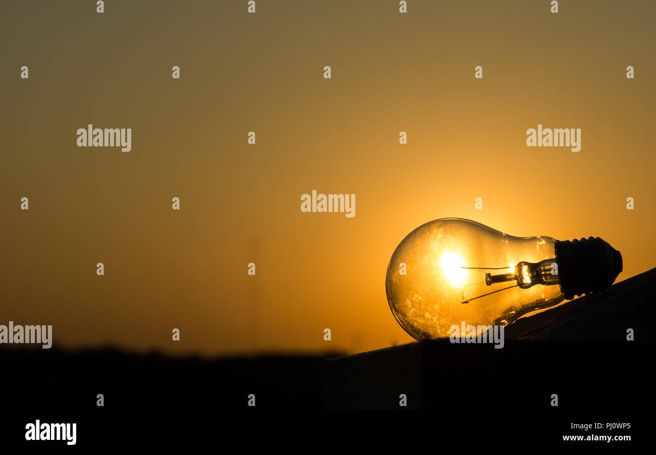 Light bulb on sunset background, light of sun in incandescent lamp ...