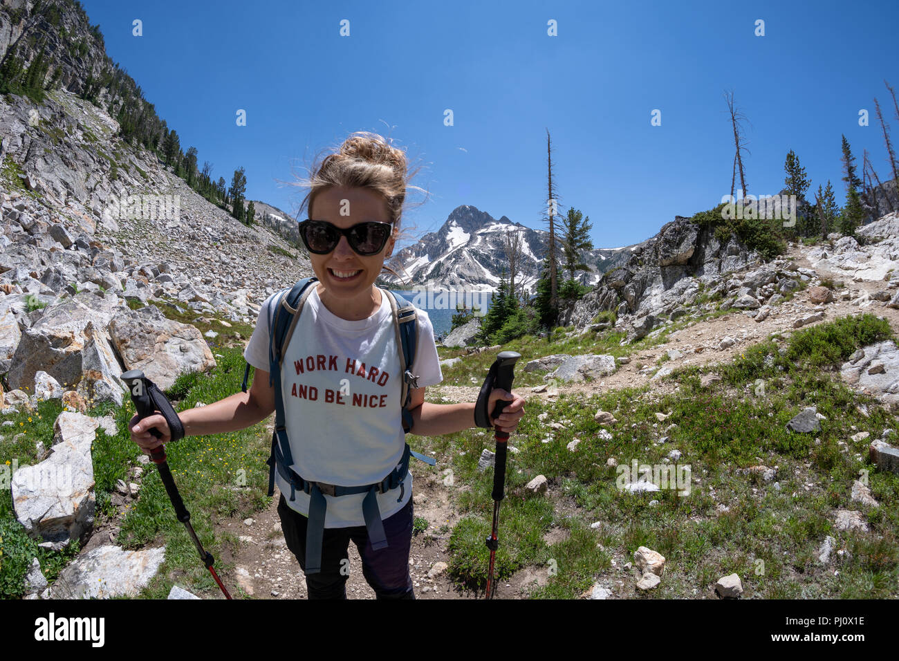Woman hiker stands on the trail of Sawtooth Lake in Idaho’s Sawtooth Mountain Range in the ...