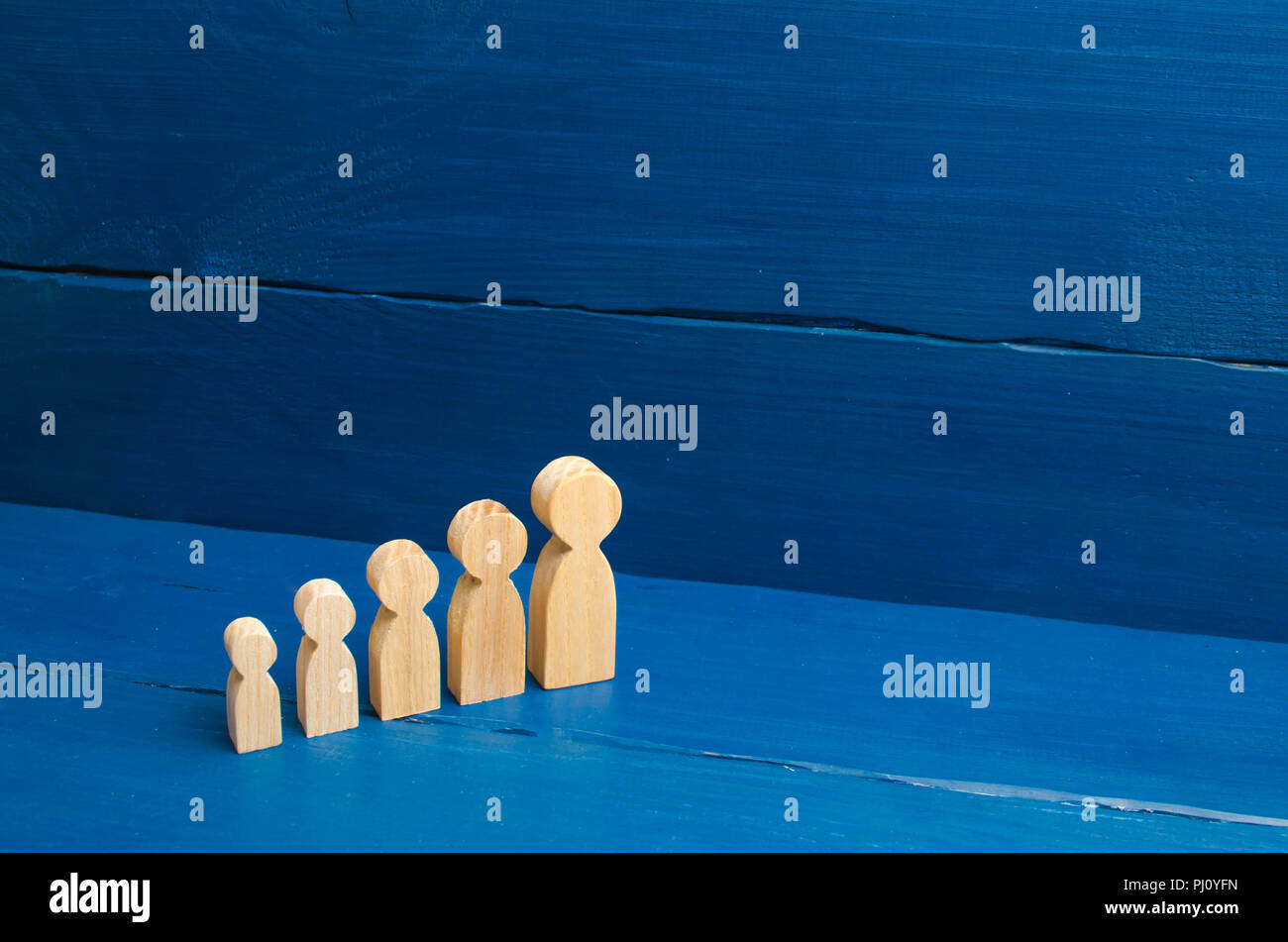 Wooden figures of people from small to large stand in a semicircle. The ...