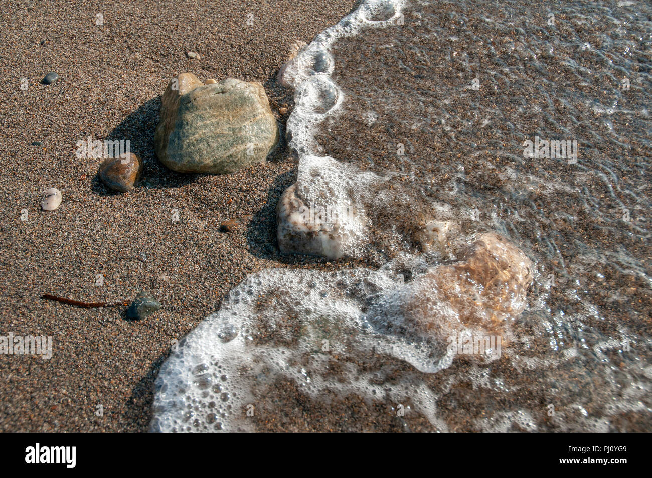 A group of pebbles by the sea shore interacting with the tide Stock ...