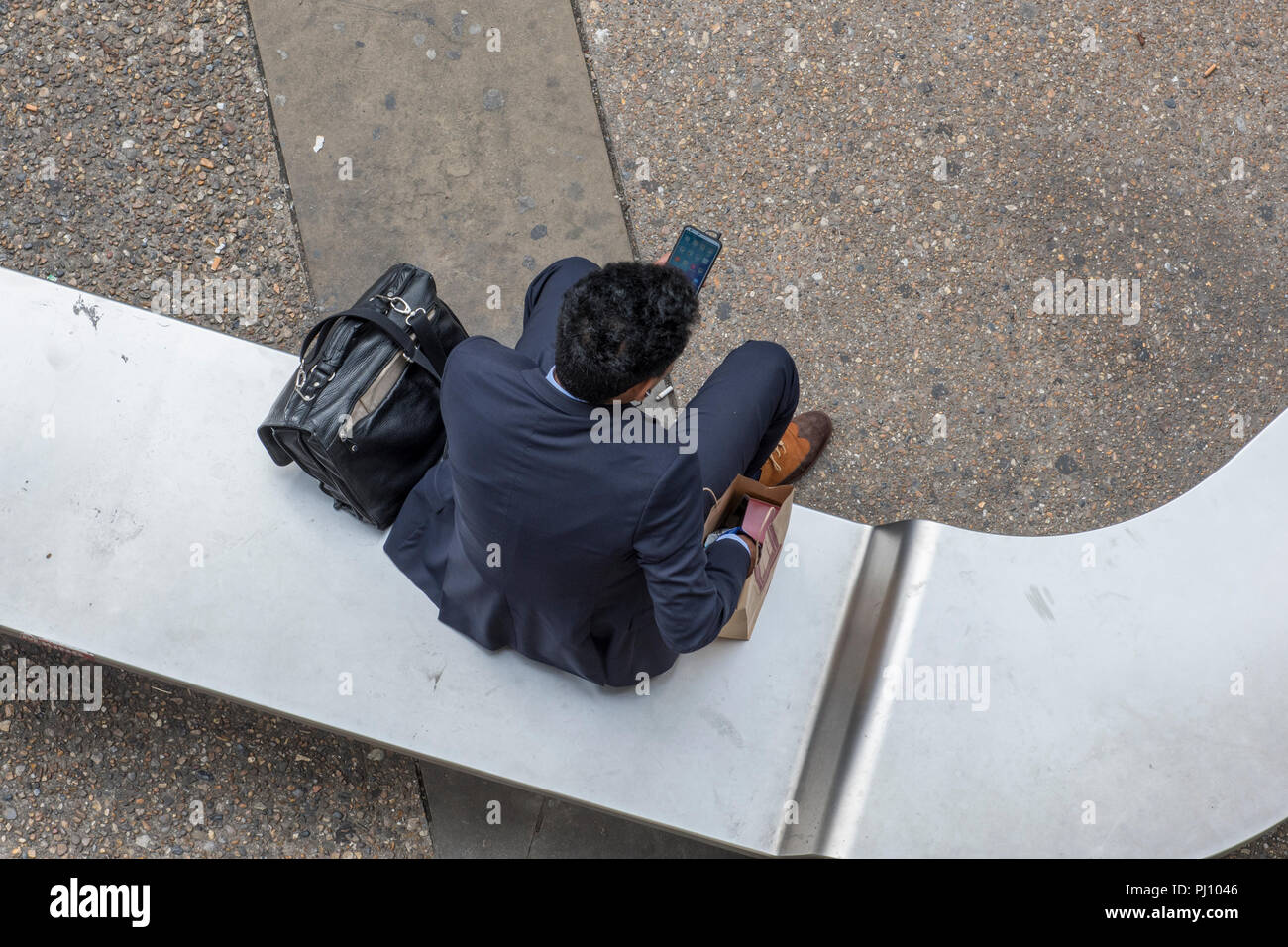 businessman wearing a smart suit in central London sitting on a metal ...