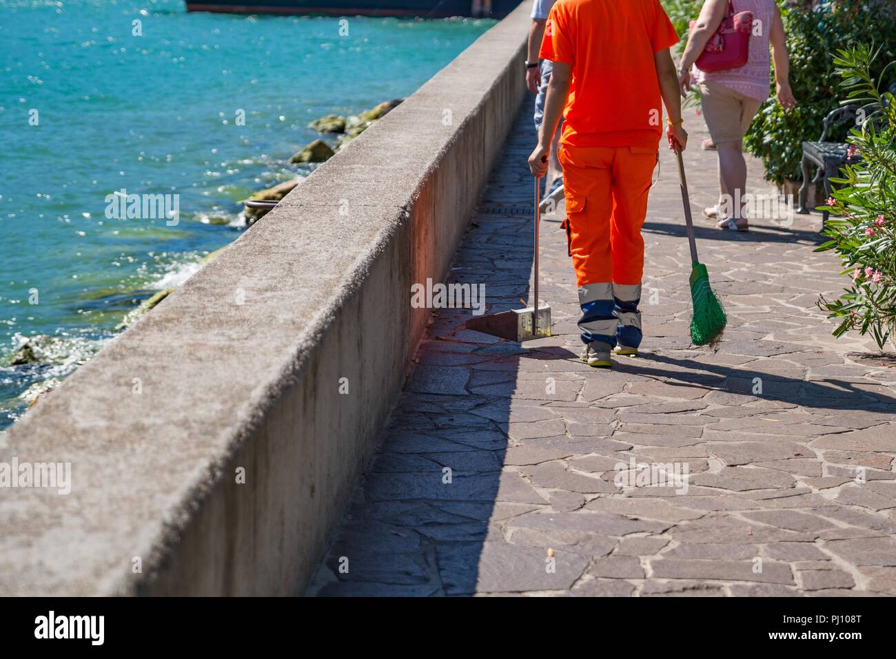 City cleaning service worker in reflective uniform sweeping street ...