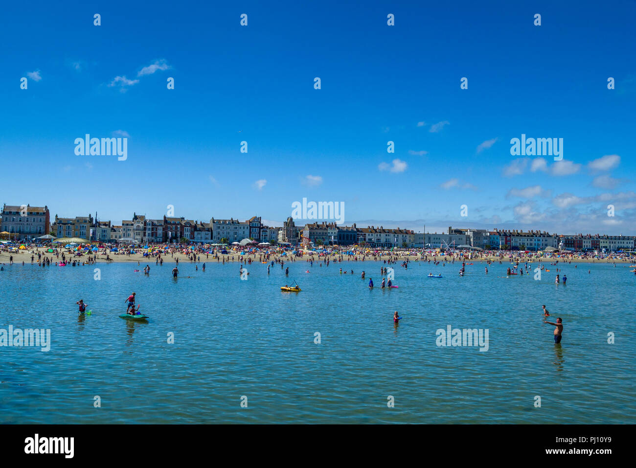 People enjoying the warm weather and shallow waters by Weymouth beach ...