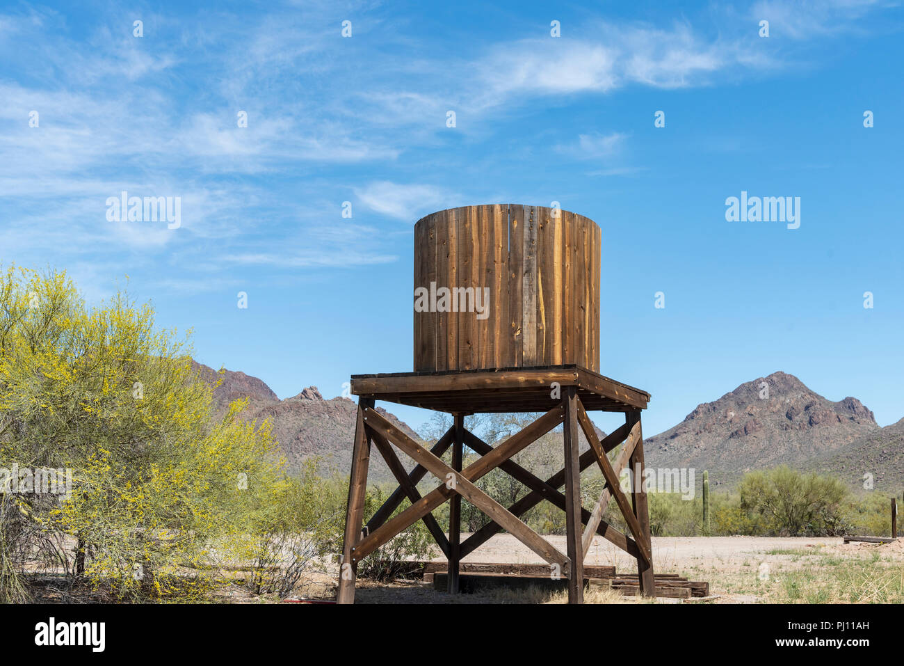 Wooden water tower on wood platform under bright blue sky with white ...
