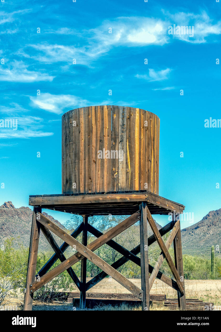 Old wooden water tower with flowering yellow trees and barren rock ...
