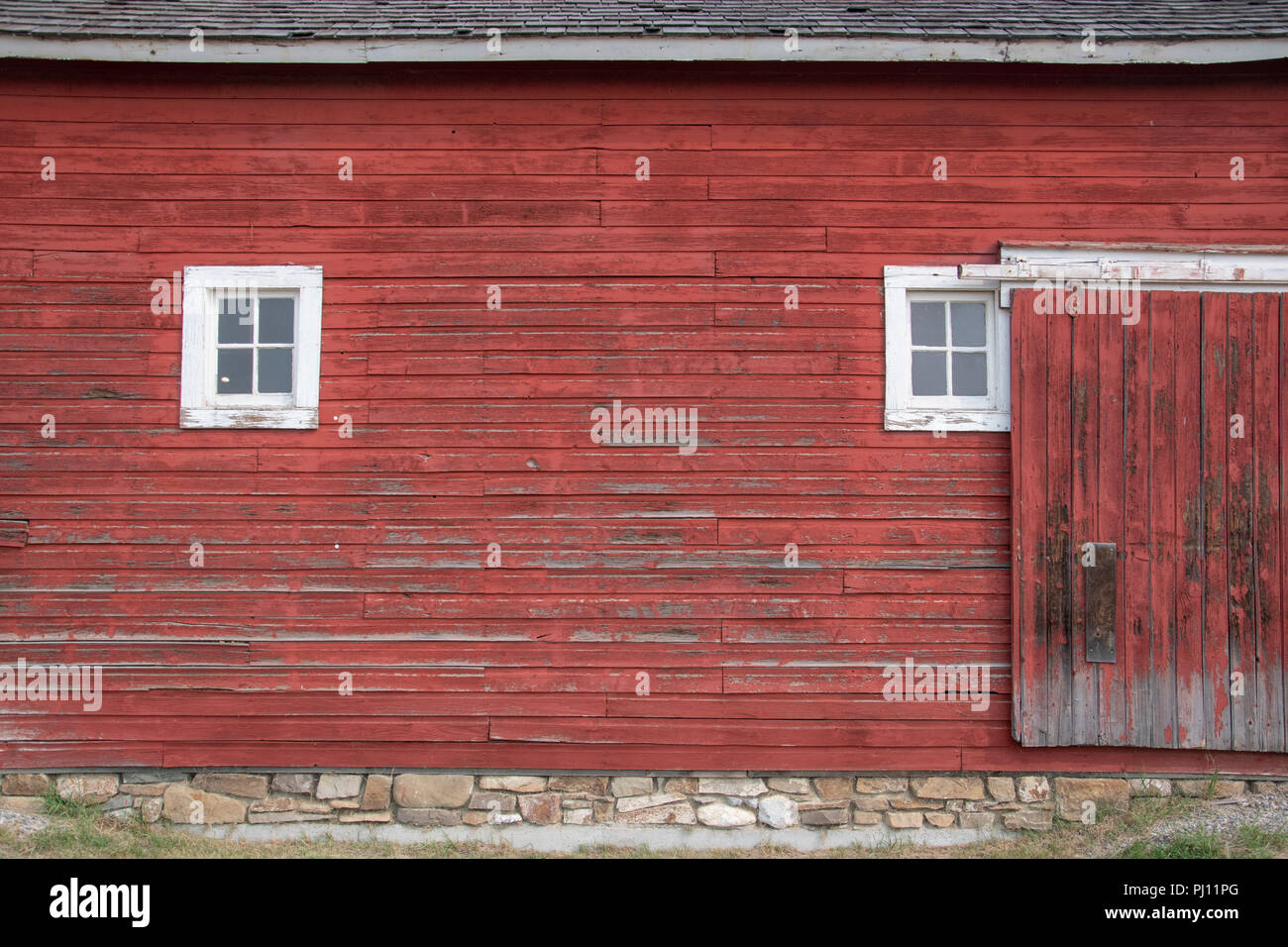 Side of an old red barn with white framed square windows and sliding ...