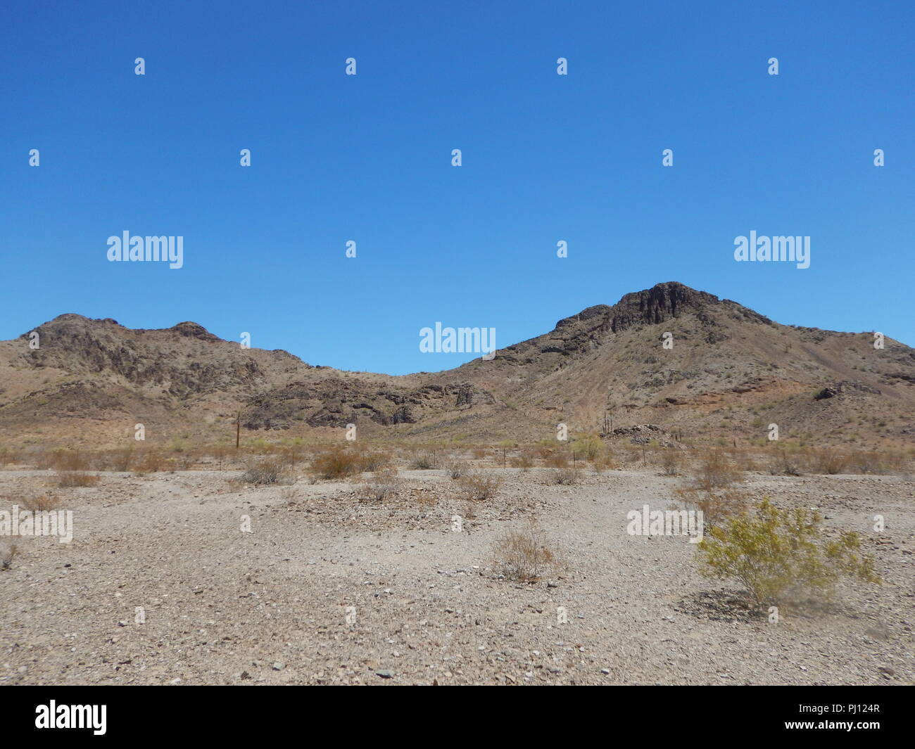 Dry desert field with mountain under blue sky Stock Photo - Alamy