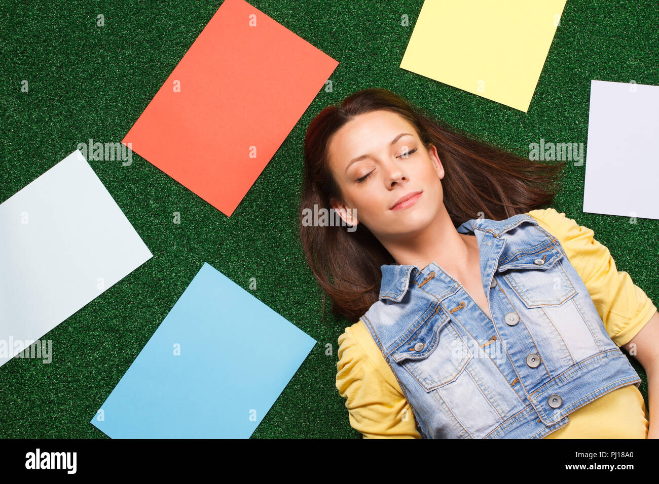 Beautiful young woman is lying on the grass and napping with a empty ...