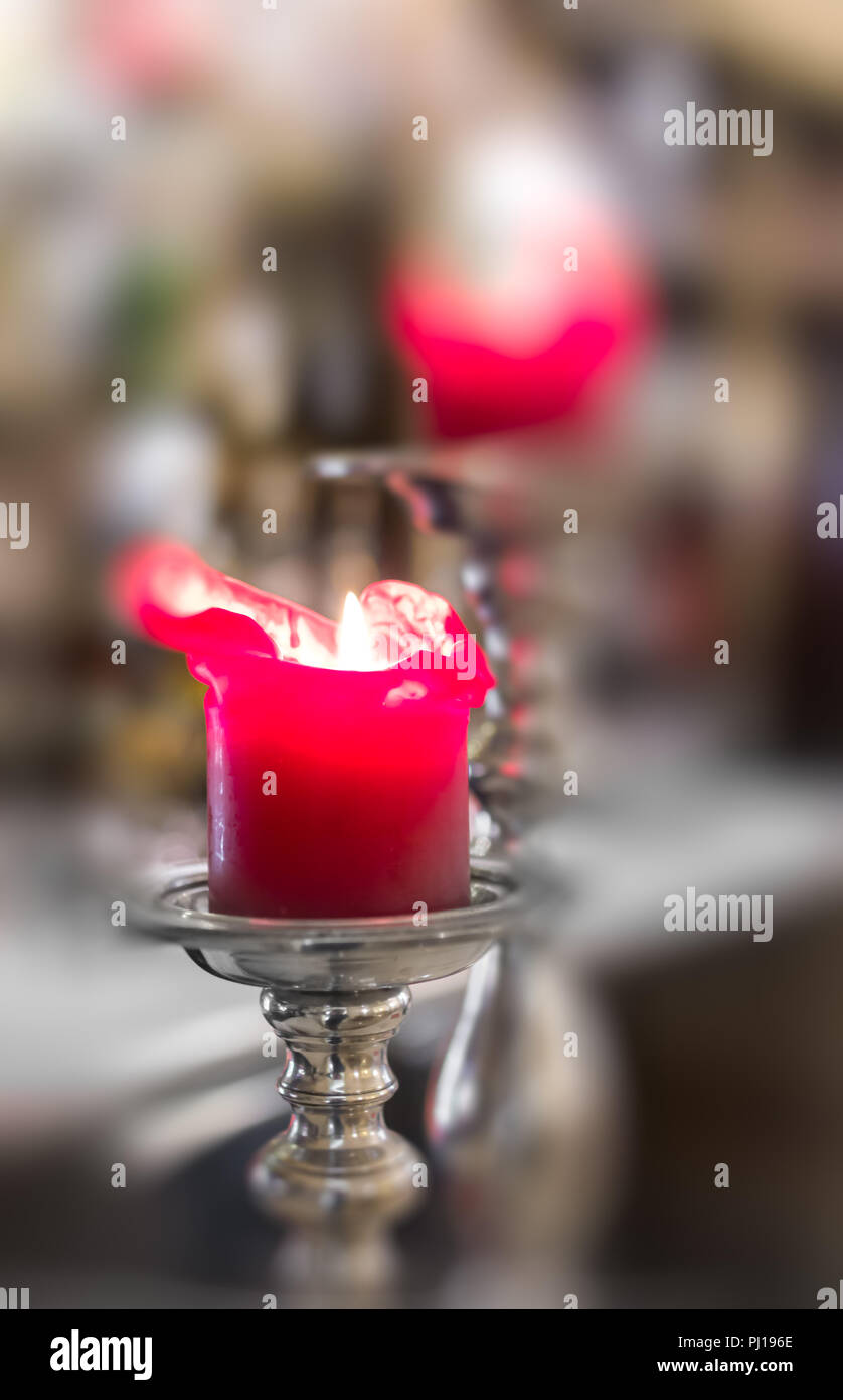 Close-up detail of red candle in silver candlestick lighting up a ...
