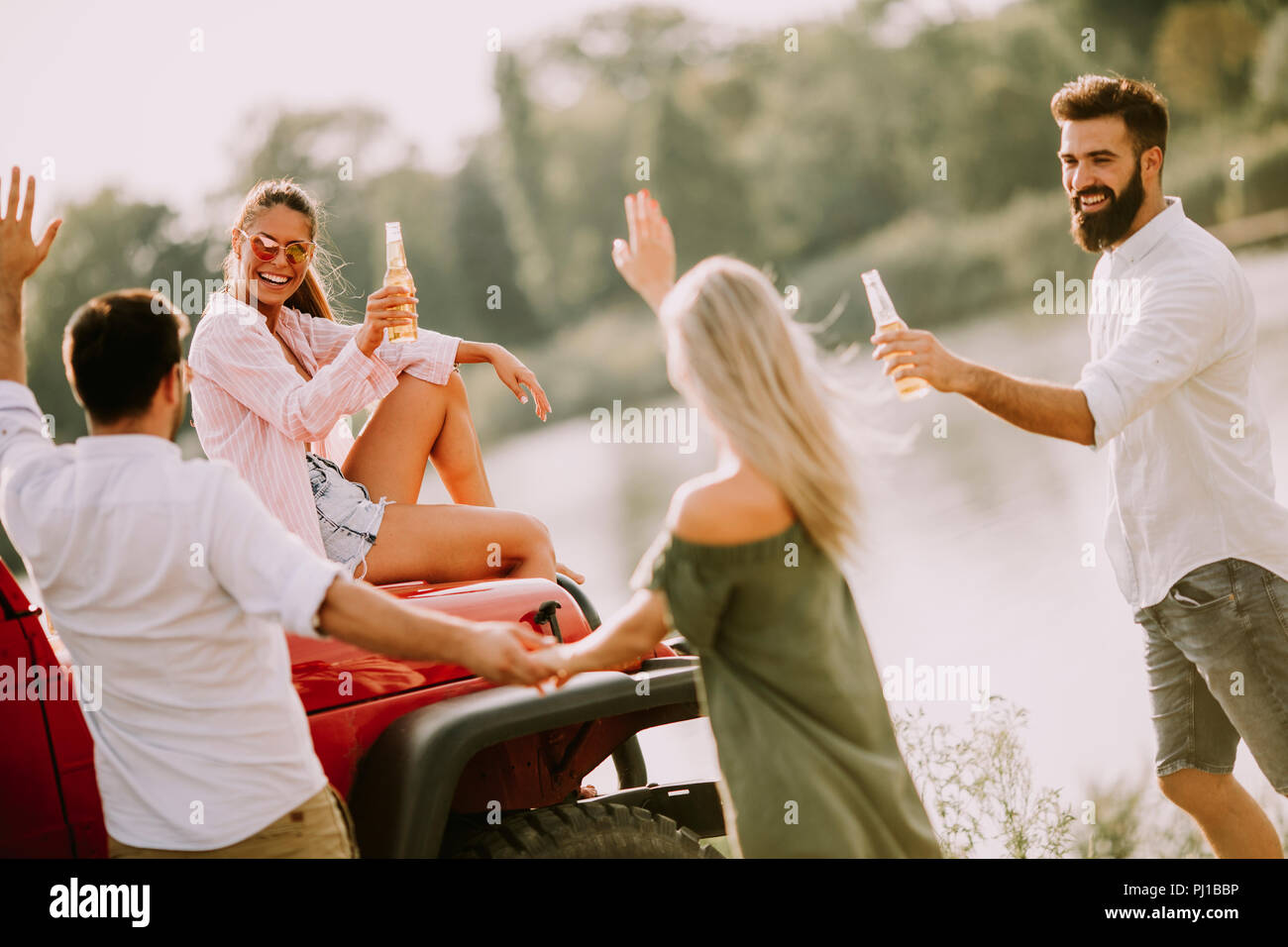 Four young people having fun in convertible car by river Stock Photo ...