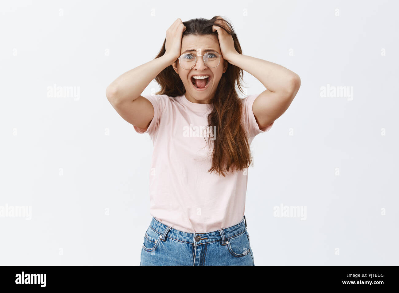 Studio shot of panicking desperate woman in despair wearing glasses and ...