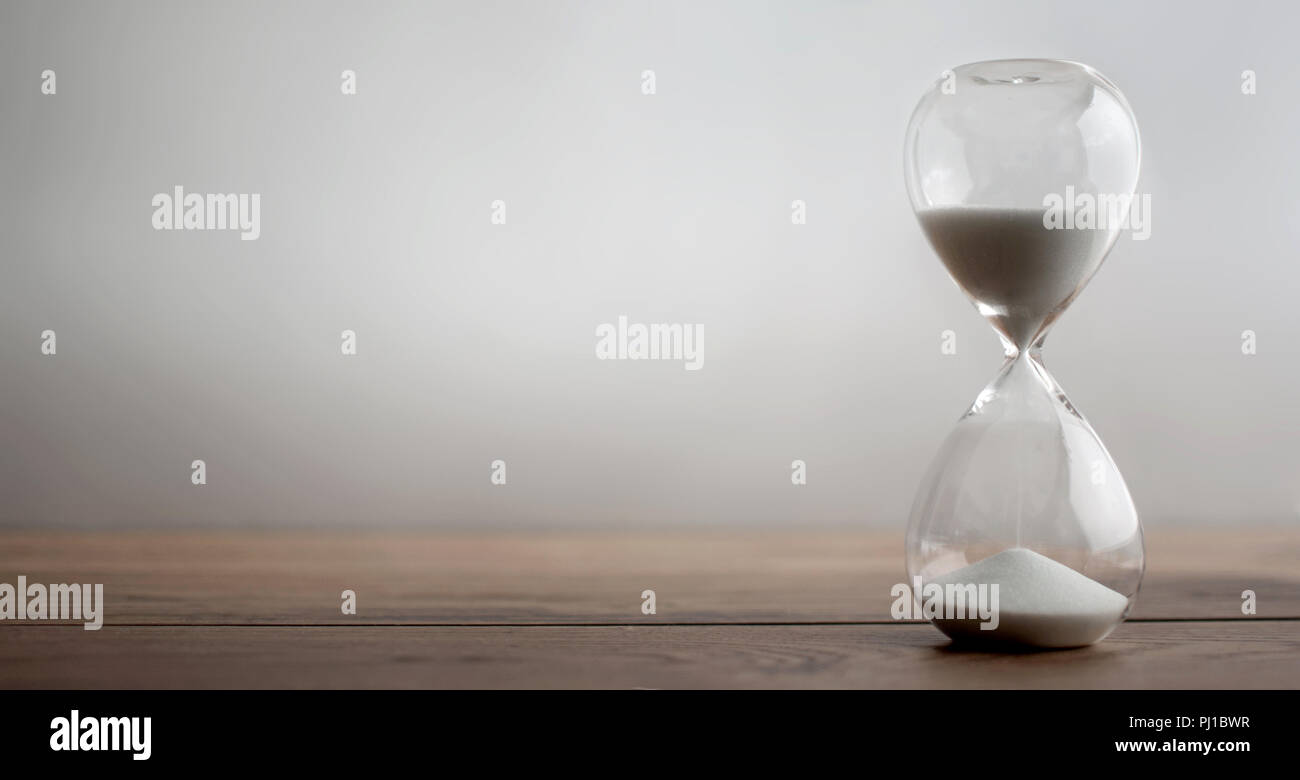 Sand flowing through hourglass Stock Photo - Alamy