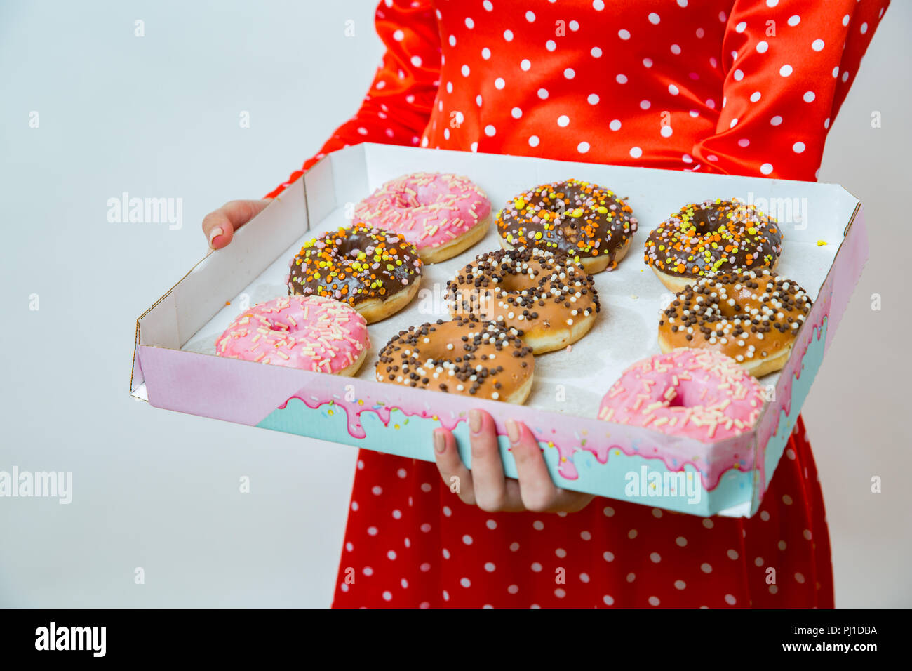 Female hands holding box with colorful donuts. girl treats sweets at a ...
