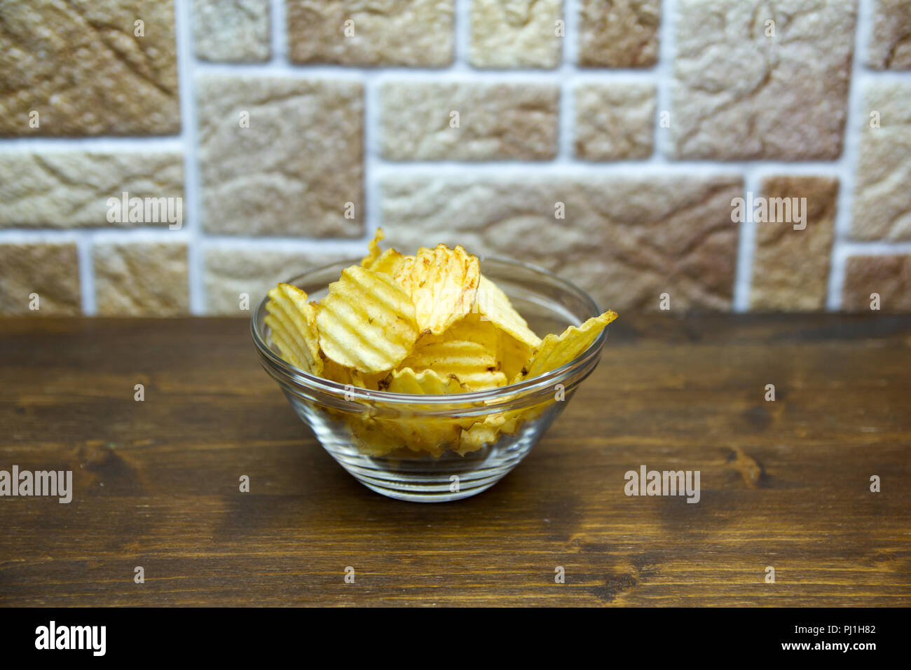 Corrugated chips inside a bowl on a wooden table viewed from above ...