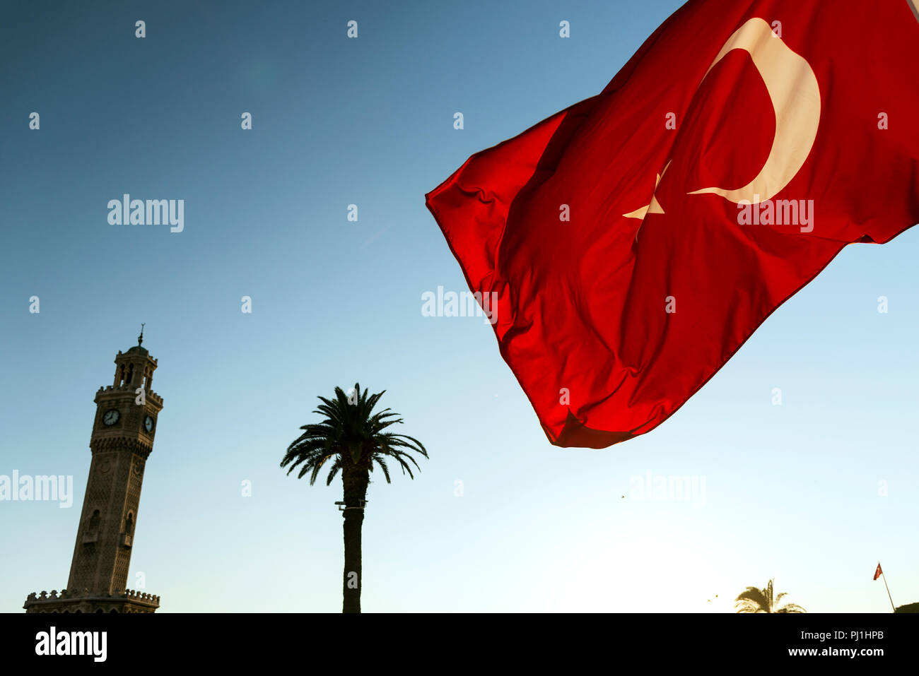 Izmirs clock tower and Turkish flag waving with palm trees Stock Photo ...