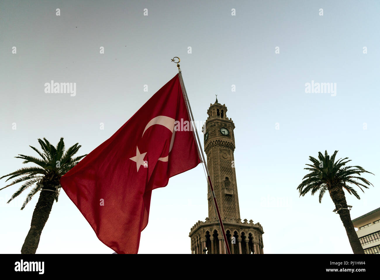 Izmirs clock tower and Turkish flag waving with palm trees Stock Photo ...