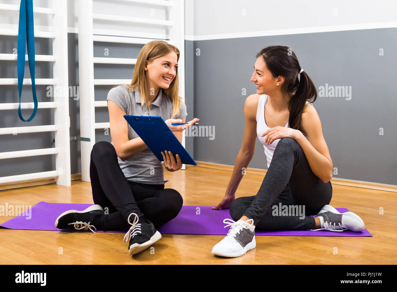 Young woman and her fitness instructor are having conversation at the ...
