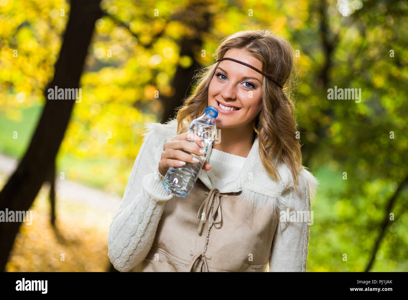 Beautiful boho girl enjoys drinking water in the park Stock Photo - Alamy