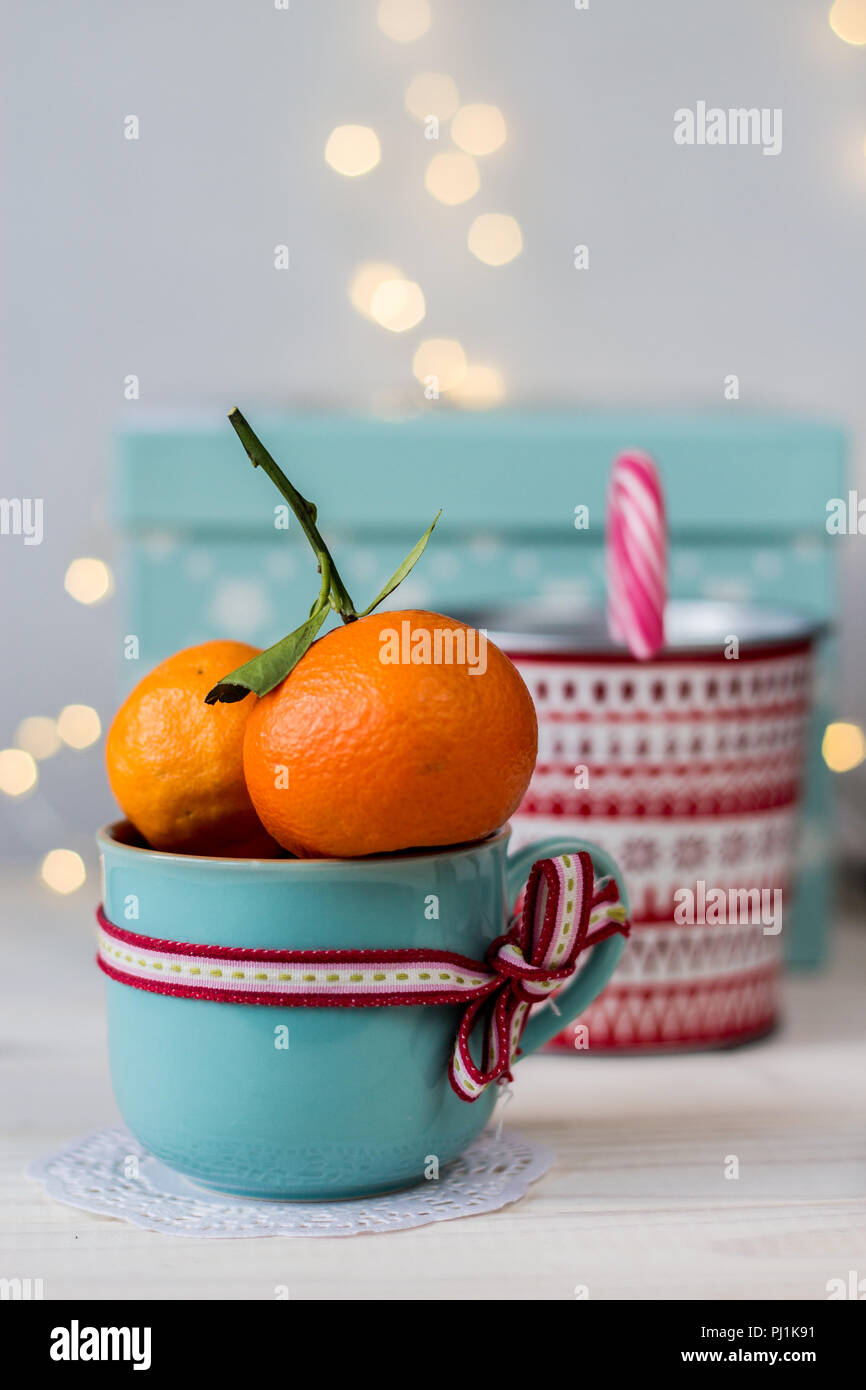 two fresh tangerines in a ceramic, blue cup with ribbon and christmas ...