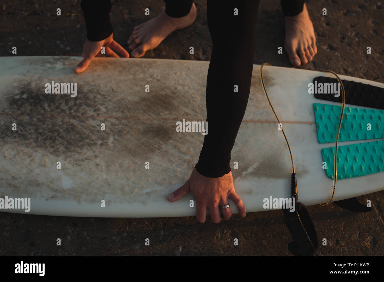 Surfer holding up surfboard on the beach hi-res stock photography and ...