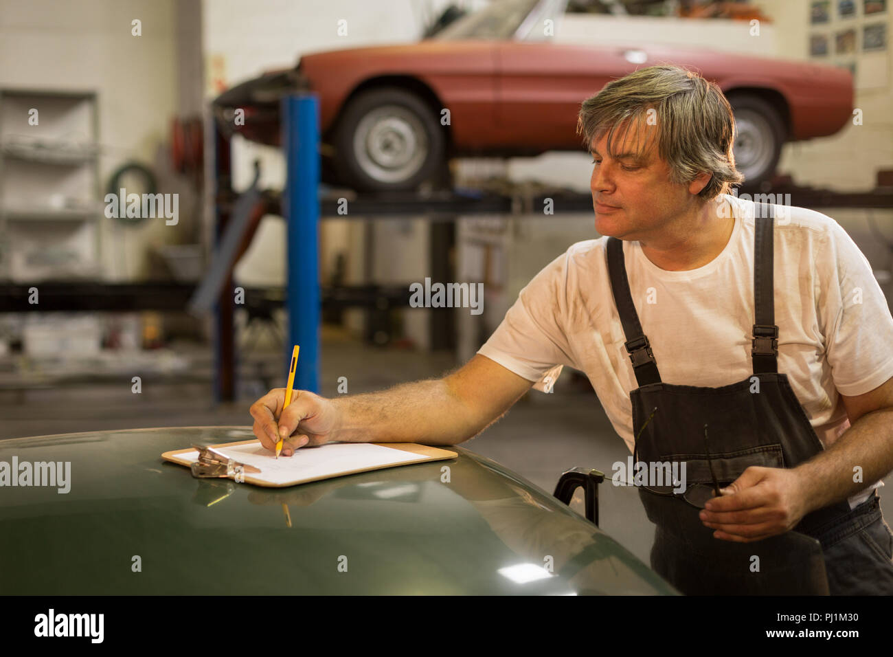 Male mechanic writing on clipboard Stock Photo - Alamy