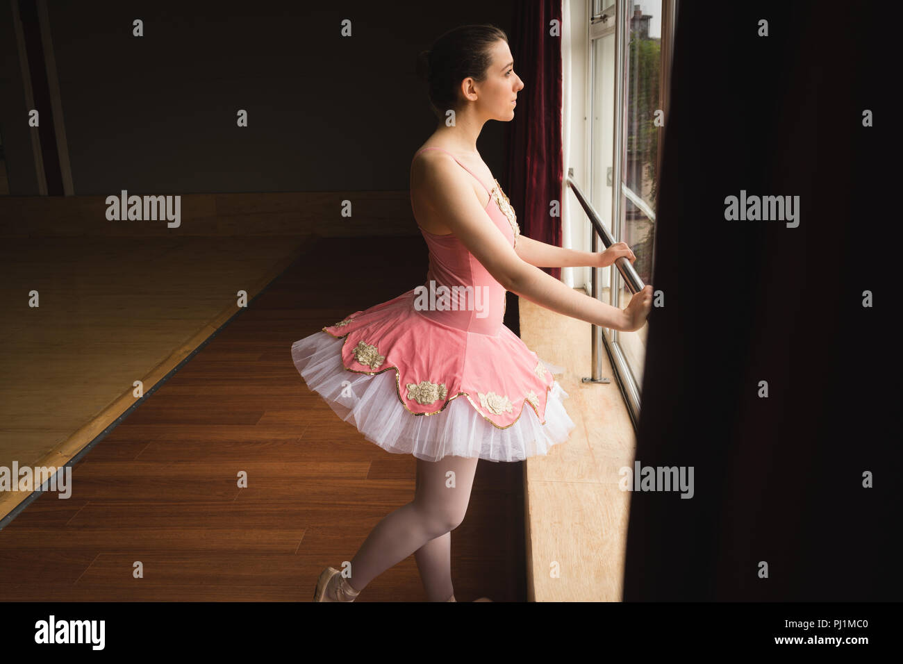 Ballerina looking through window in dance studio Stock Photo - Alamy