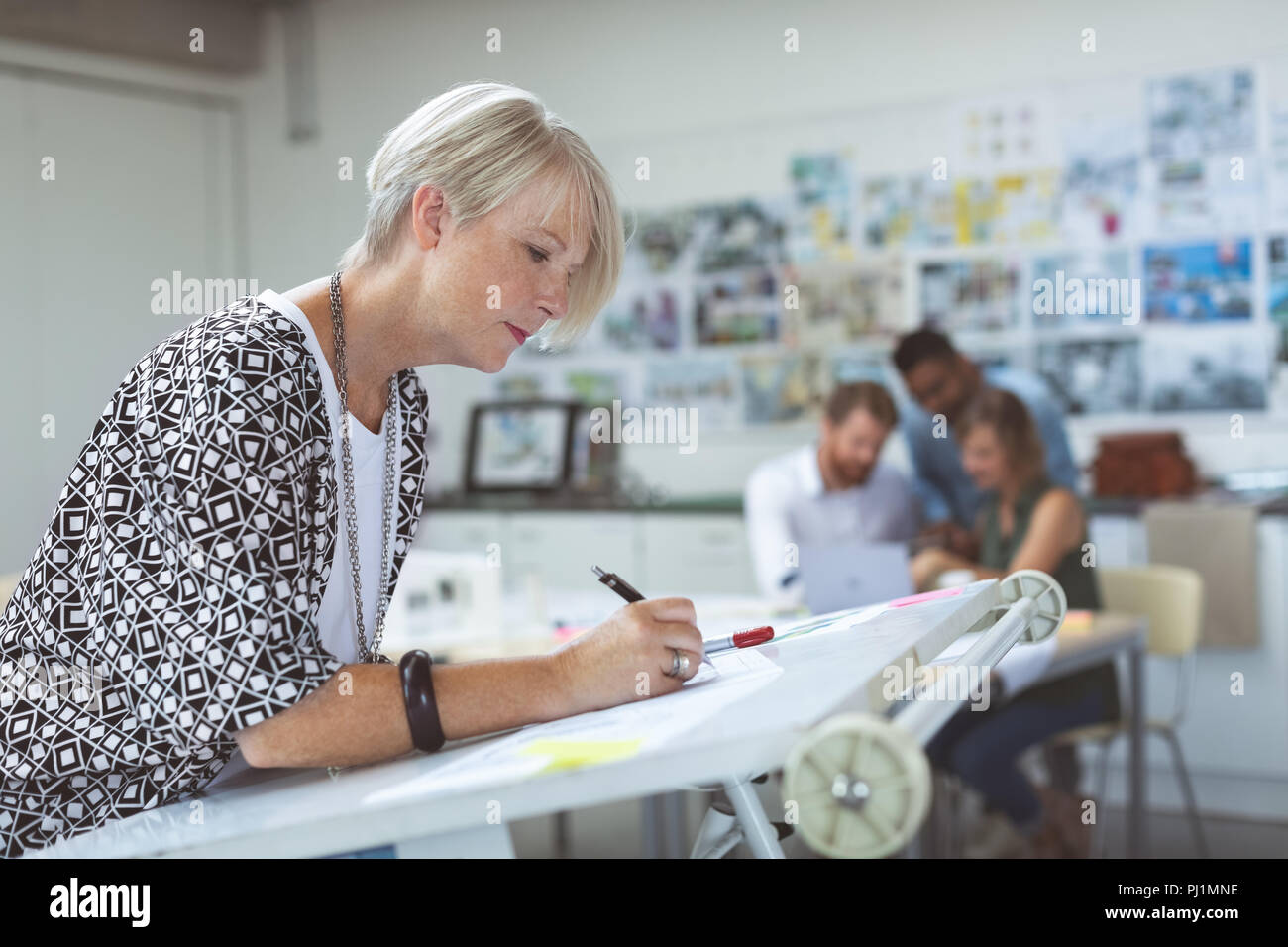 Female executive working on drafting table Stock Photo - Alamy