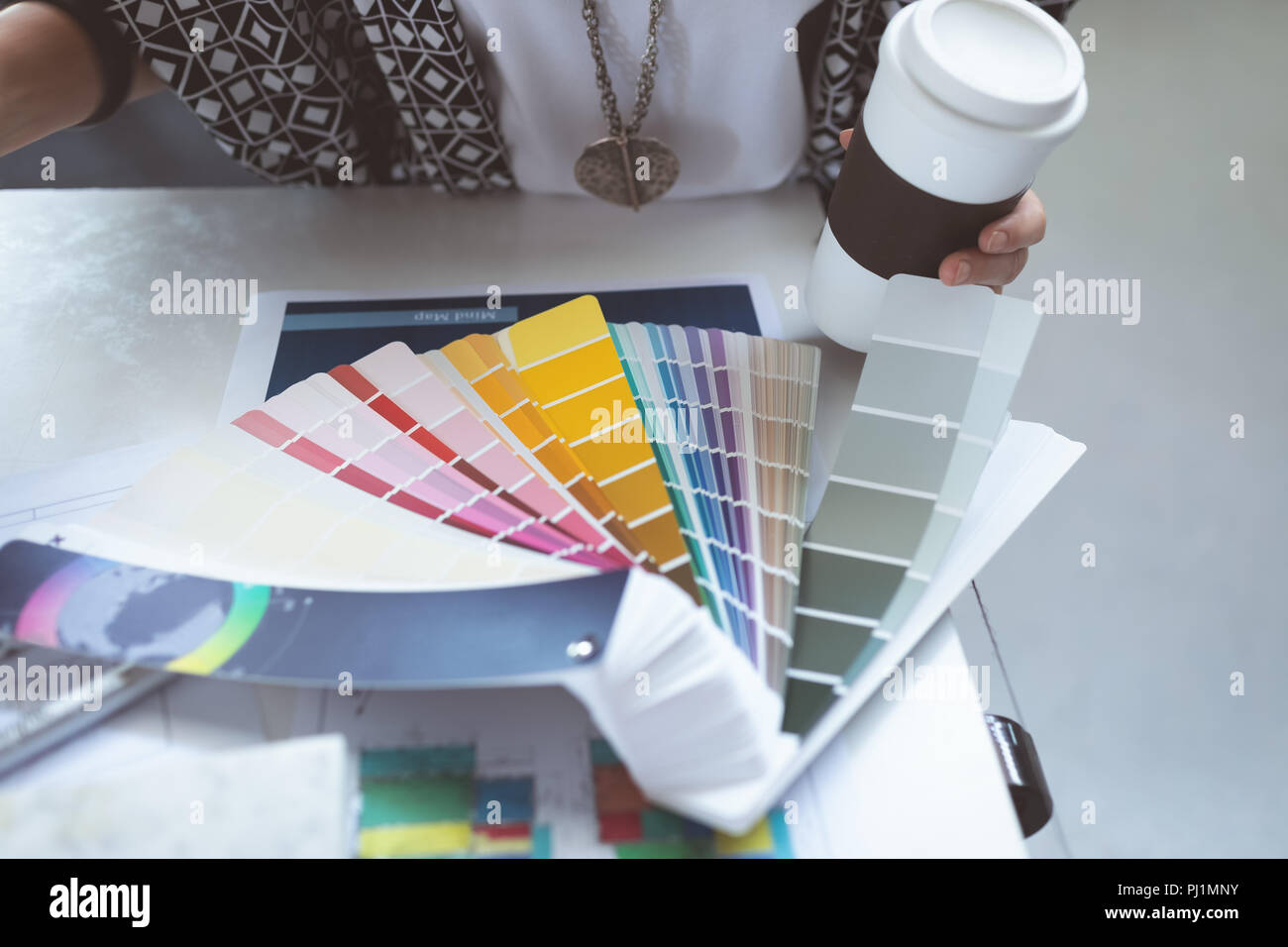 Female executive checking color swatch on drafting table in office ...