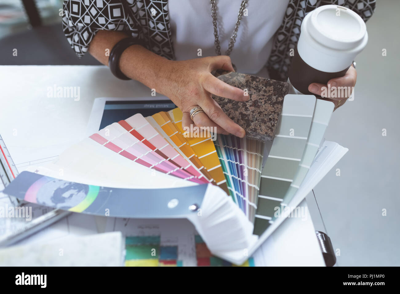 Female executive checking color swatch on drafting table in office ...